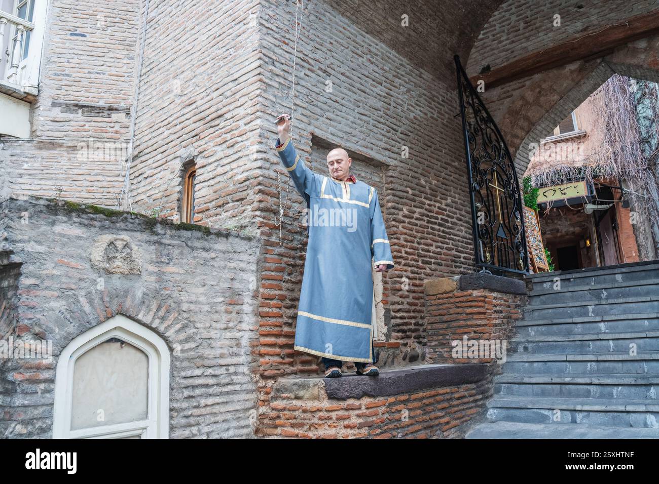 A bell ringer rings large church bells under the open sky. A ...