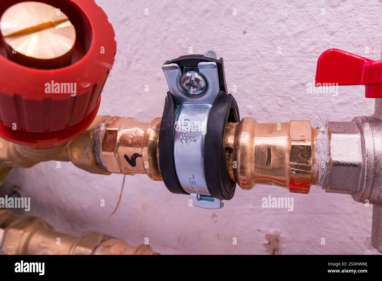 closeup of a pipe with valves fastened at a wall with a 3/4 inch clamp ...