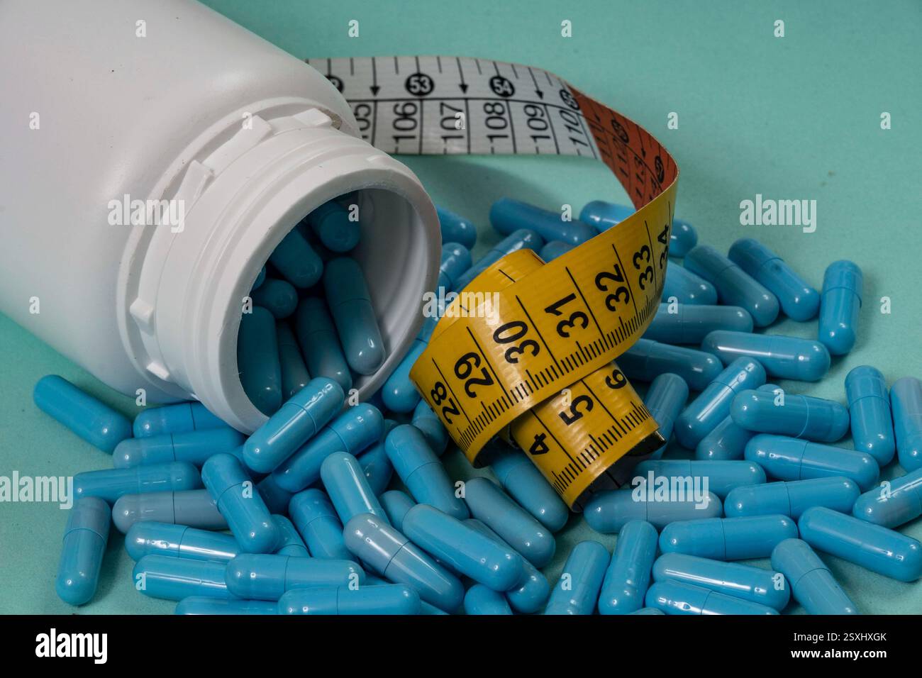A bottle of pills, some of which have spilled onto a light blue surface ...