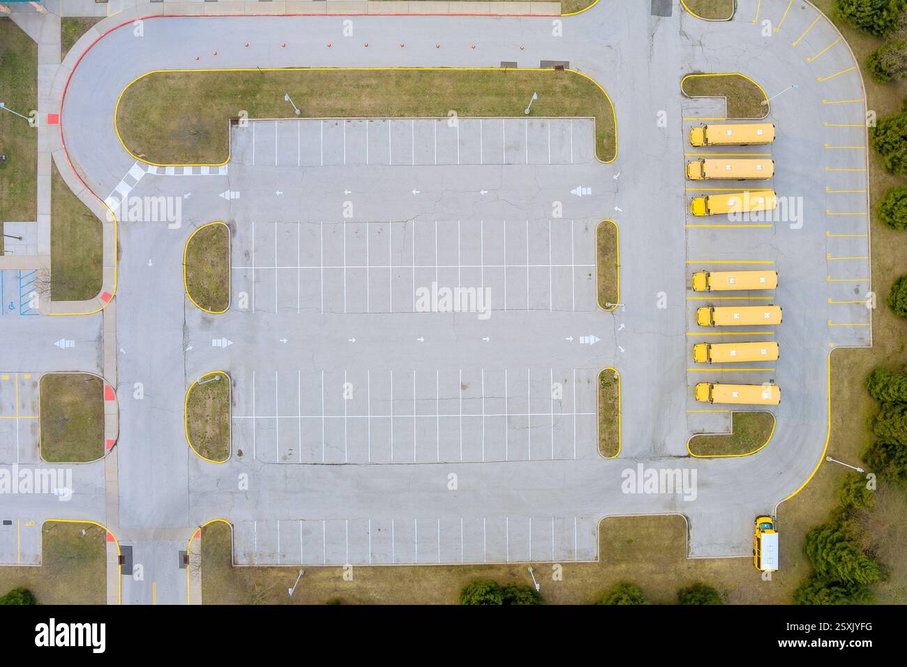 Vast parking lot is mostly empty, with yellow school buses neatly ...