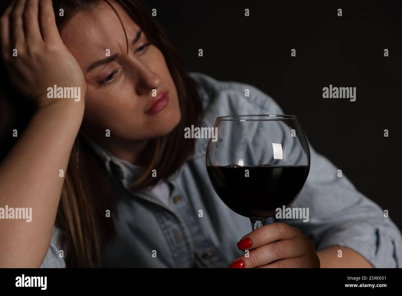Alcohol addiction. Miserable woman with wine in dark Stock Photo - Alamy