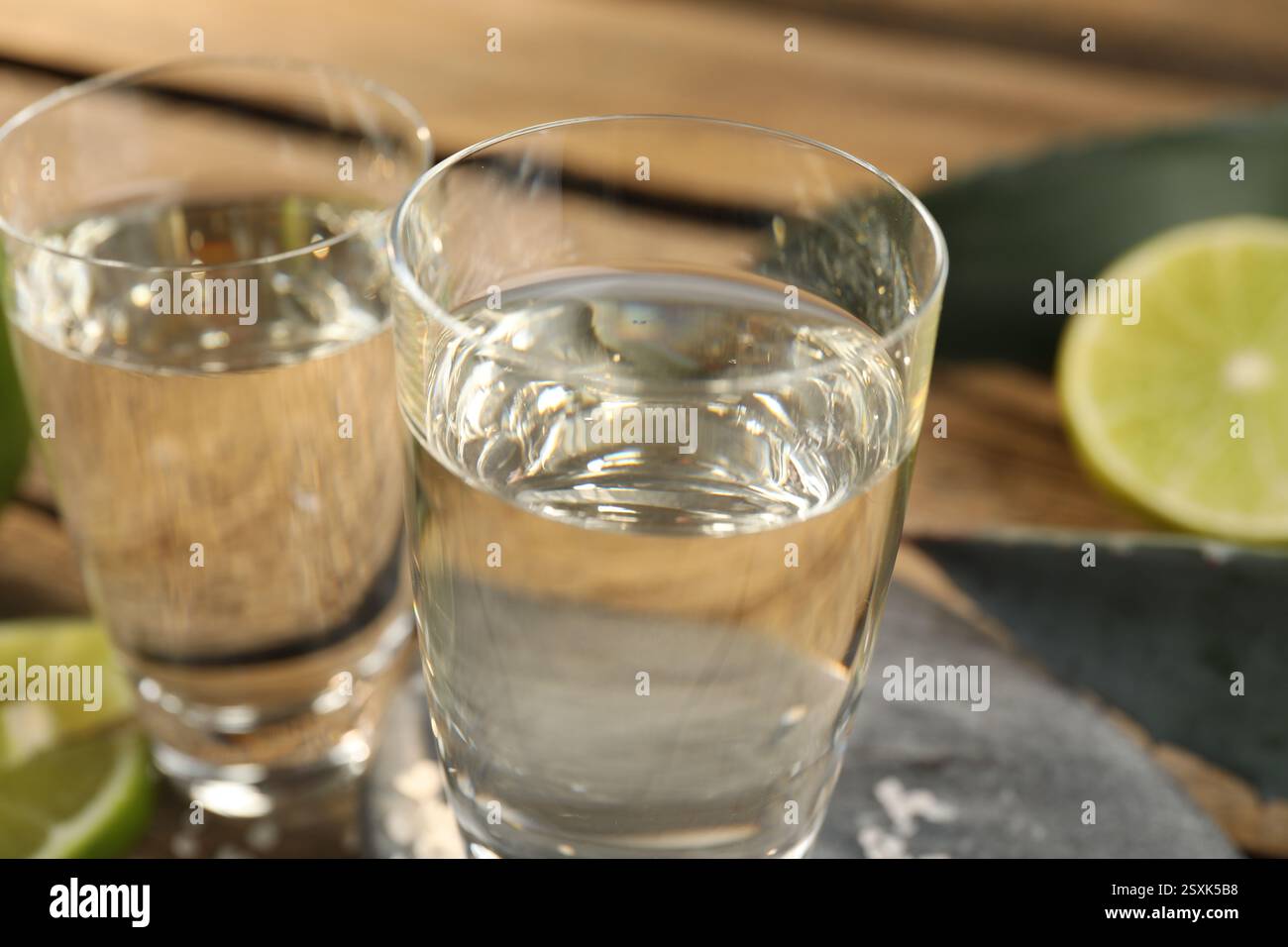 Tequila shots with limes and agave leaves on table, closeup Stock Photo ...