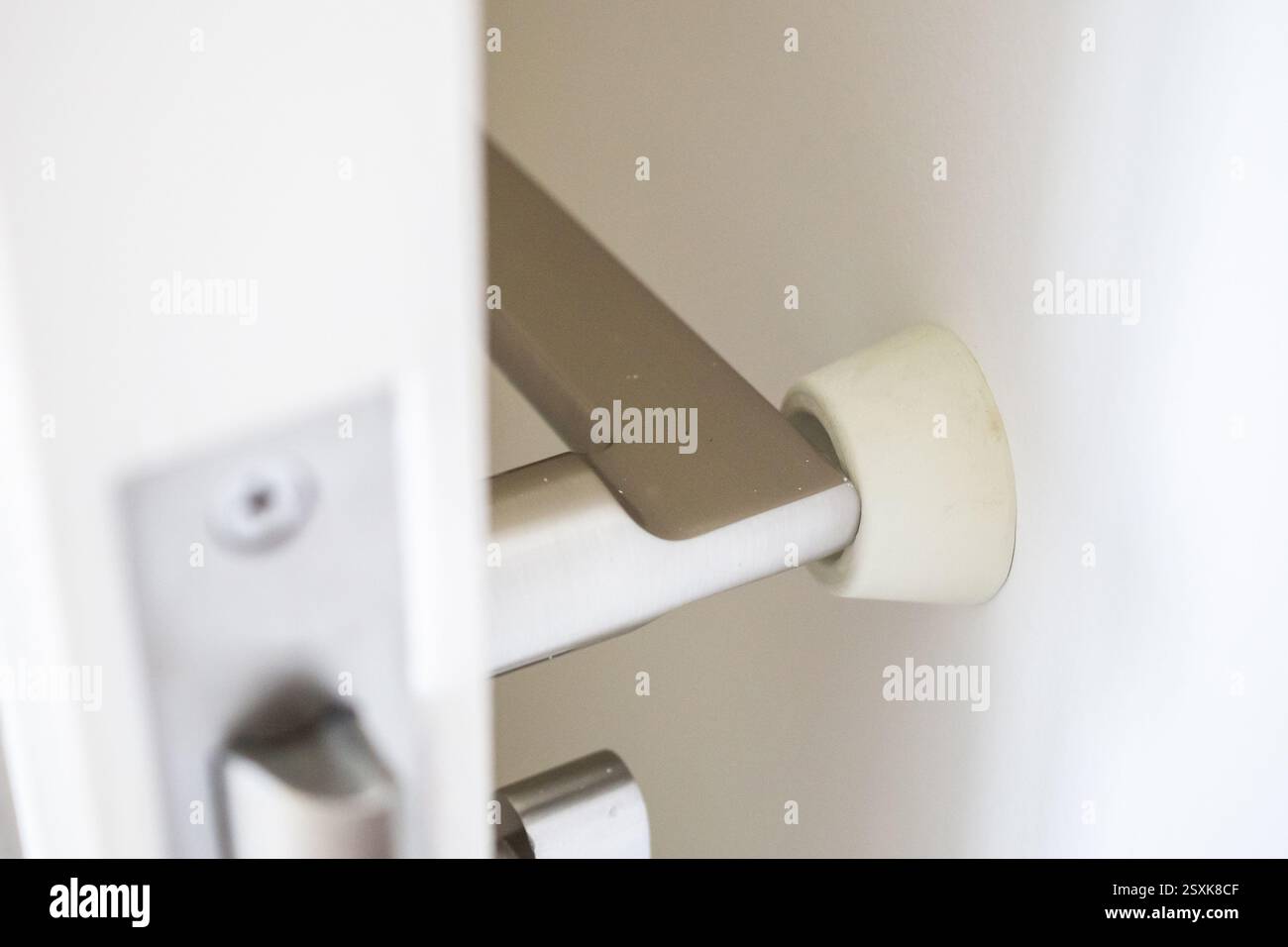 Wall mounted door stopper with modern door handle Stock Photo - Alamy
