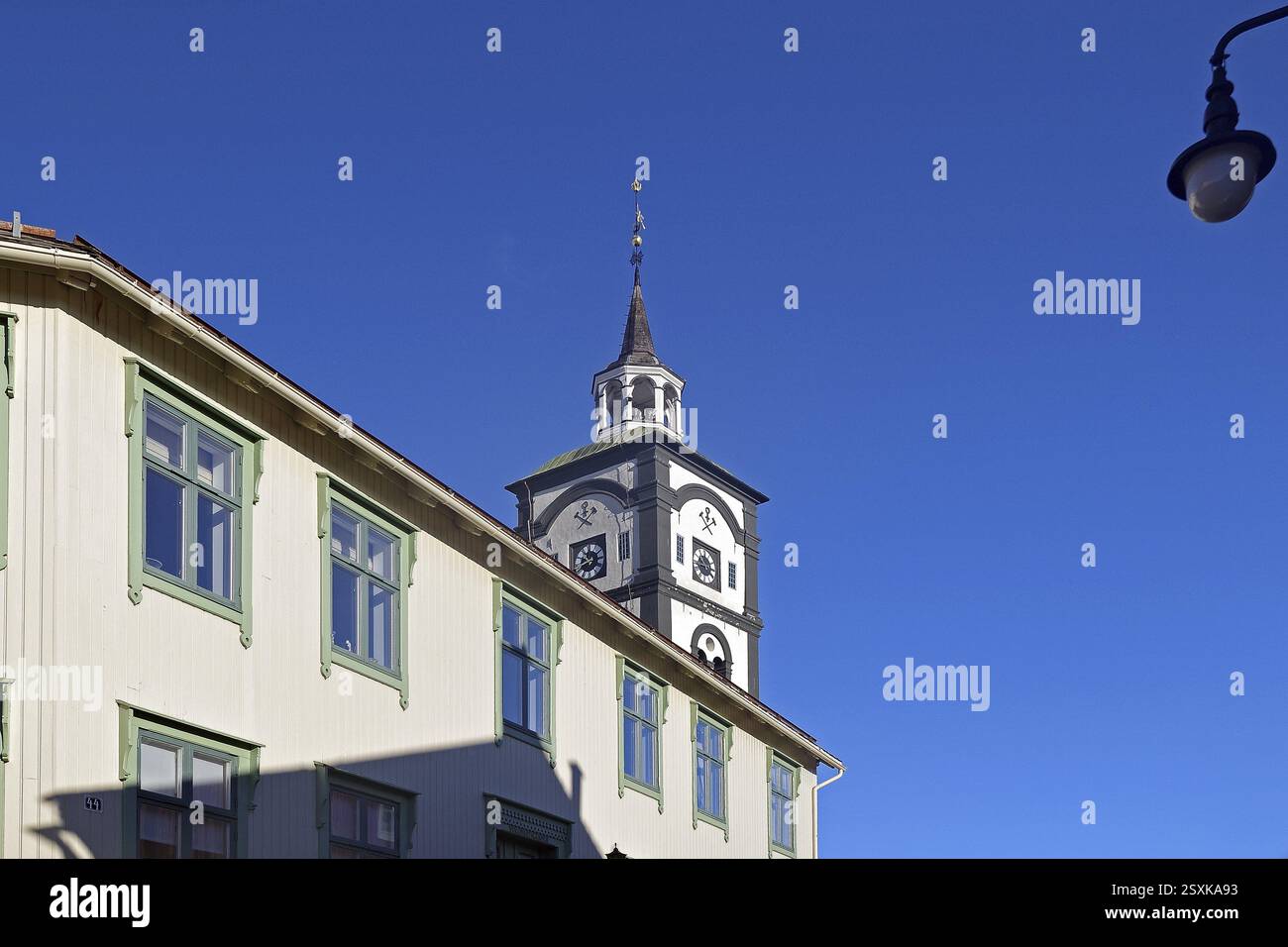 High clock tower of a church next to a light green building under a ...