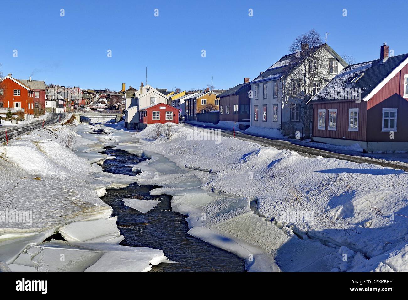 Snowy landscape with colourful wooden houses on a frozen river under a ...