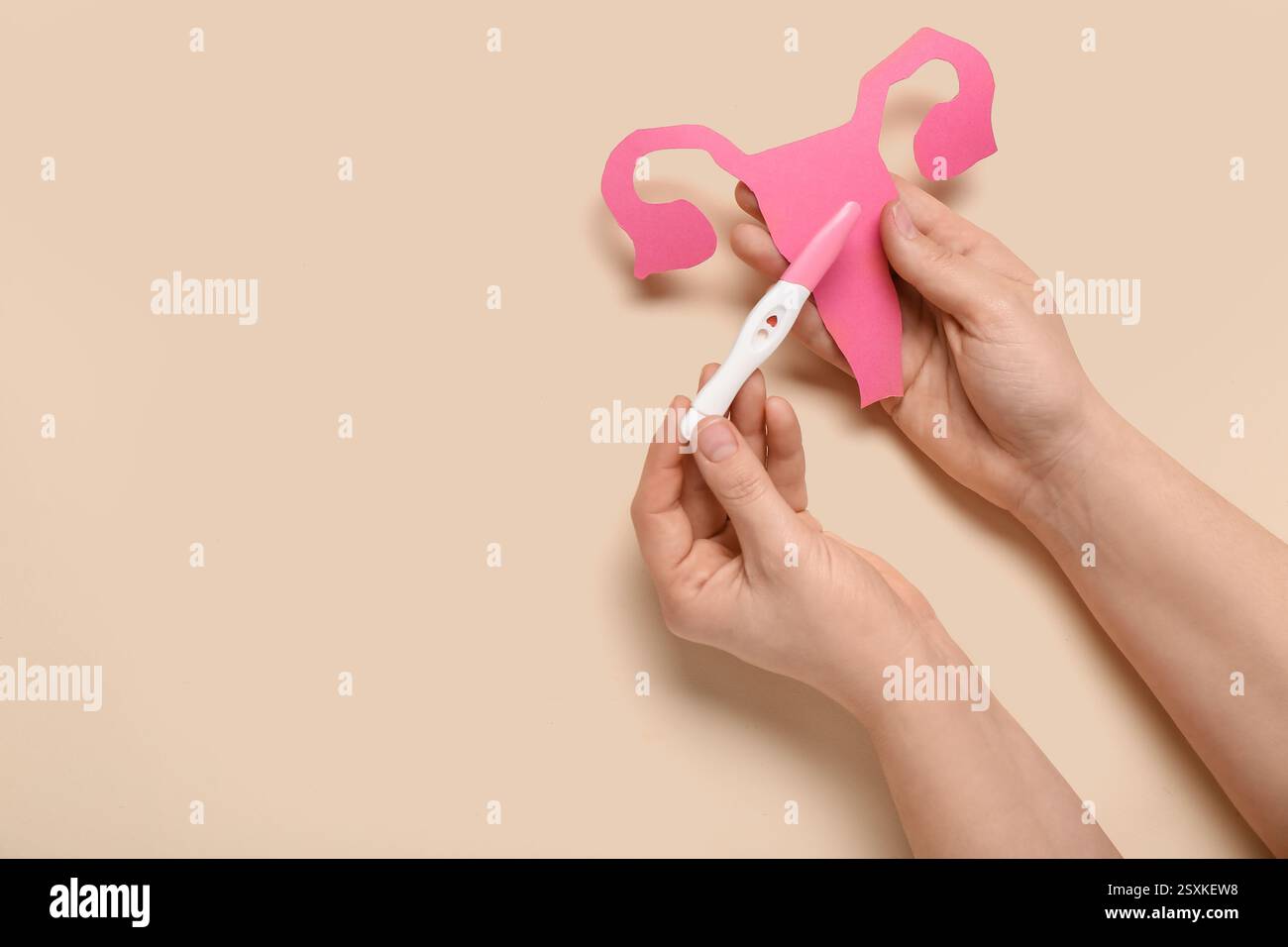 Female hands with paper uterus and pregnancy test on beige background ...
