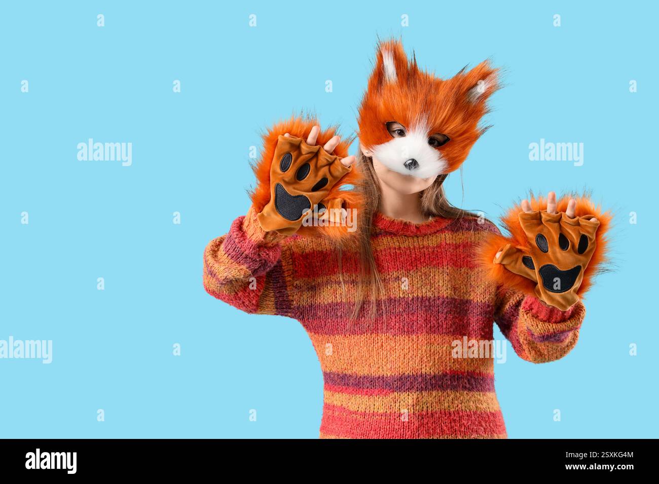 Quadrober girl in cat disguise on light blue background Stock Photo - Alamy