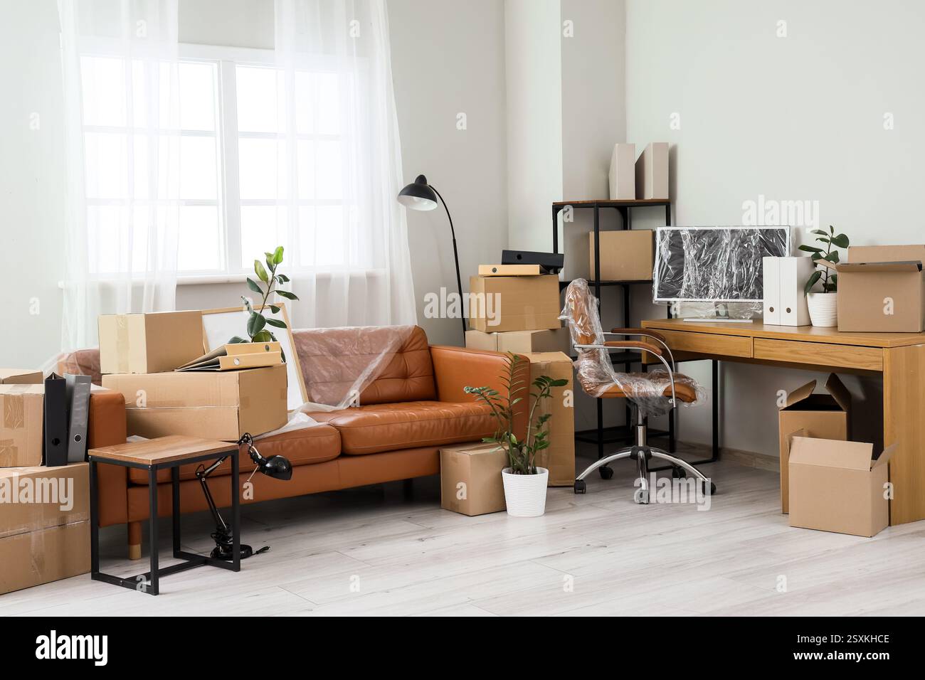 Brown sofa with workplace and cardboard boxes in office on moving day ...