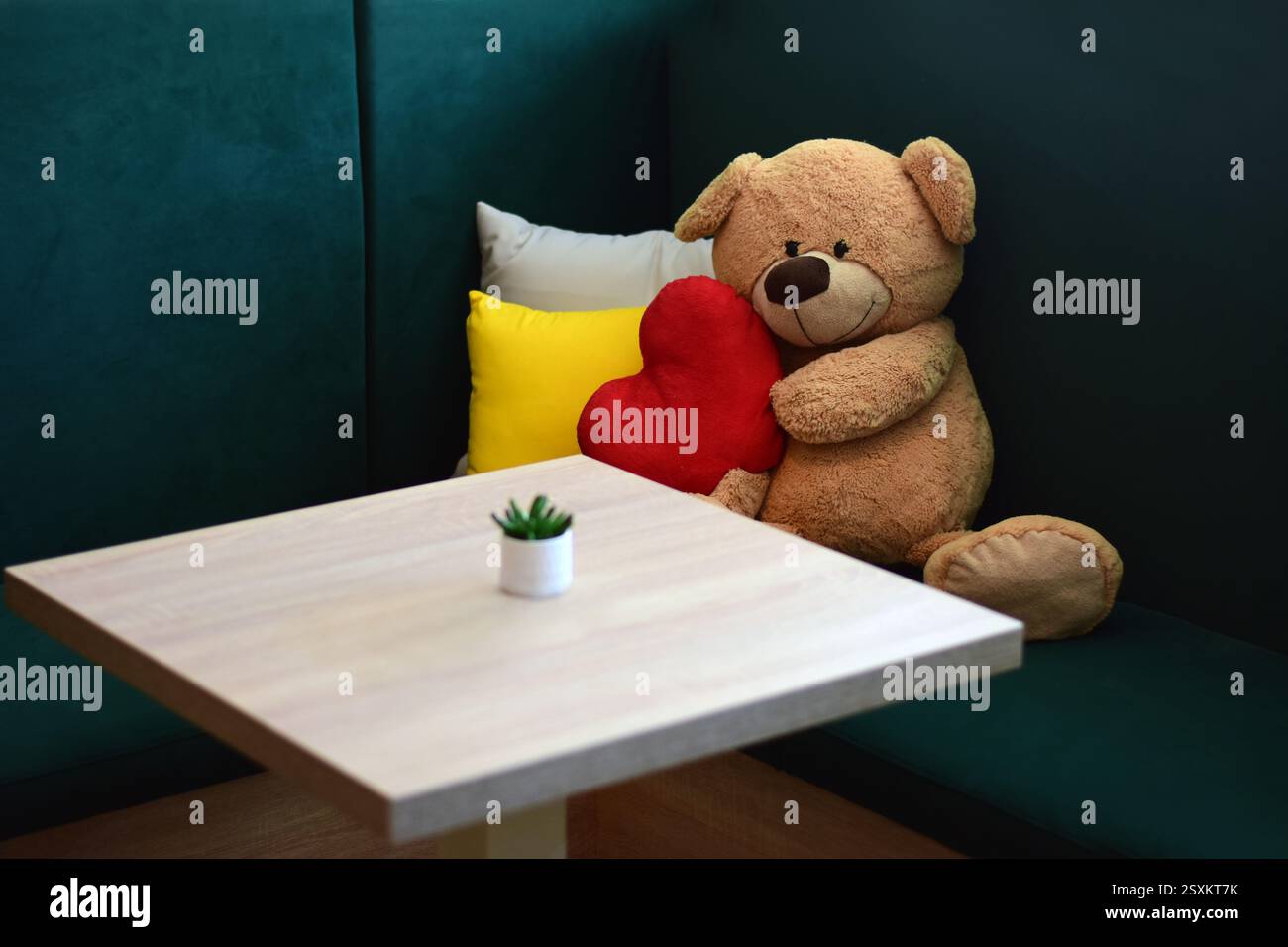 Stuffed bear holding a heart sitting alone at the table in a cafe Stock ...