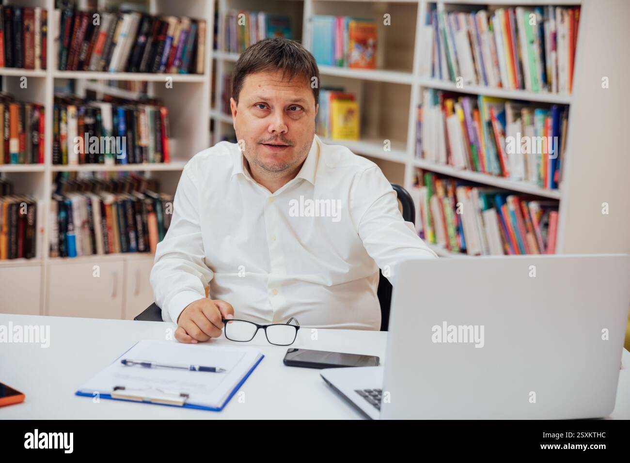 man studying at desk with laptop and books negotiating in office online ...