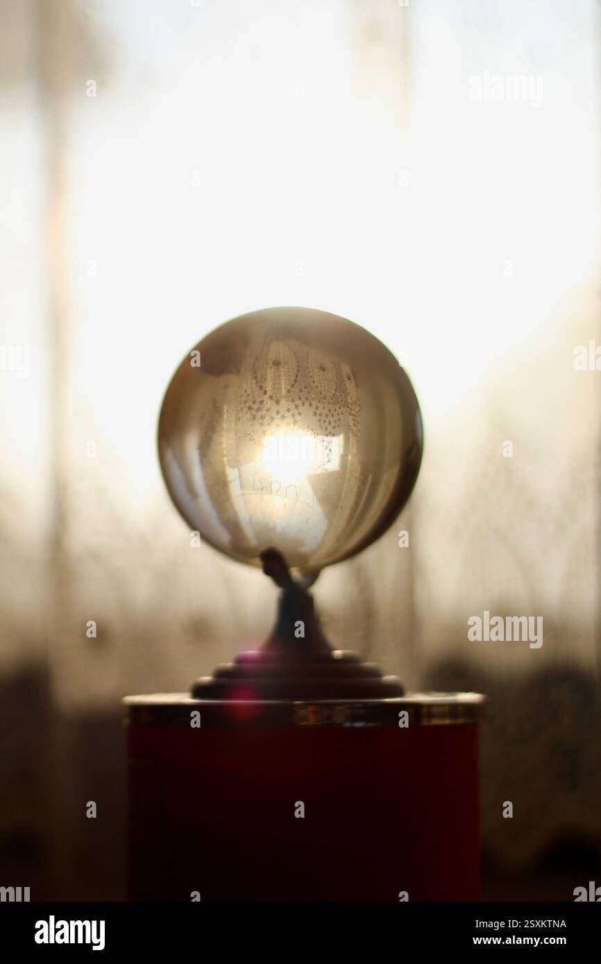 A clear glass world map globe on the metal stand on the wooden surface ...