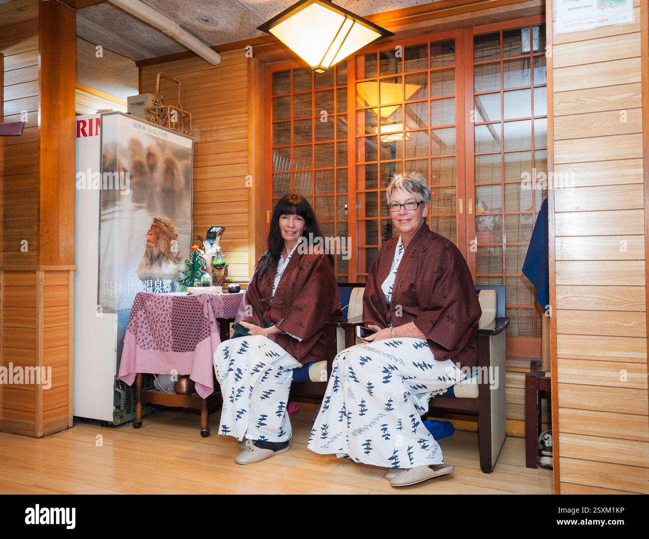 Two female tourists sit, waiting,on a traditional bench dressed in ...