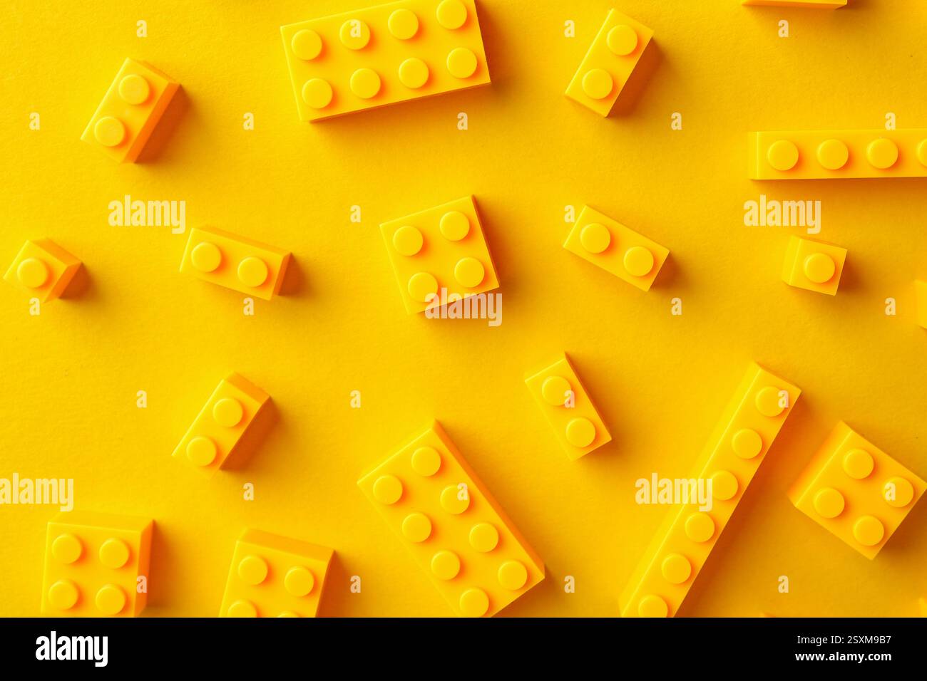 Constructor toy. Many building blocks on yellow background, flat lay ...
