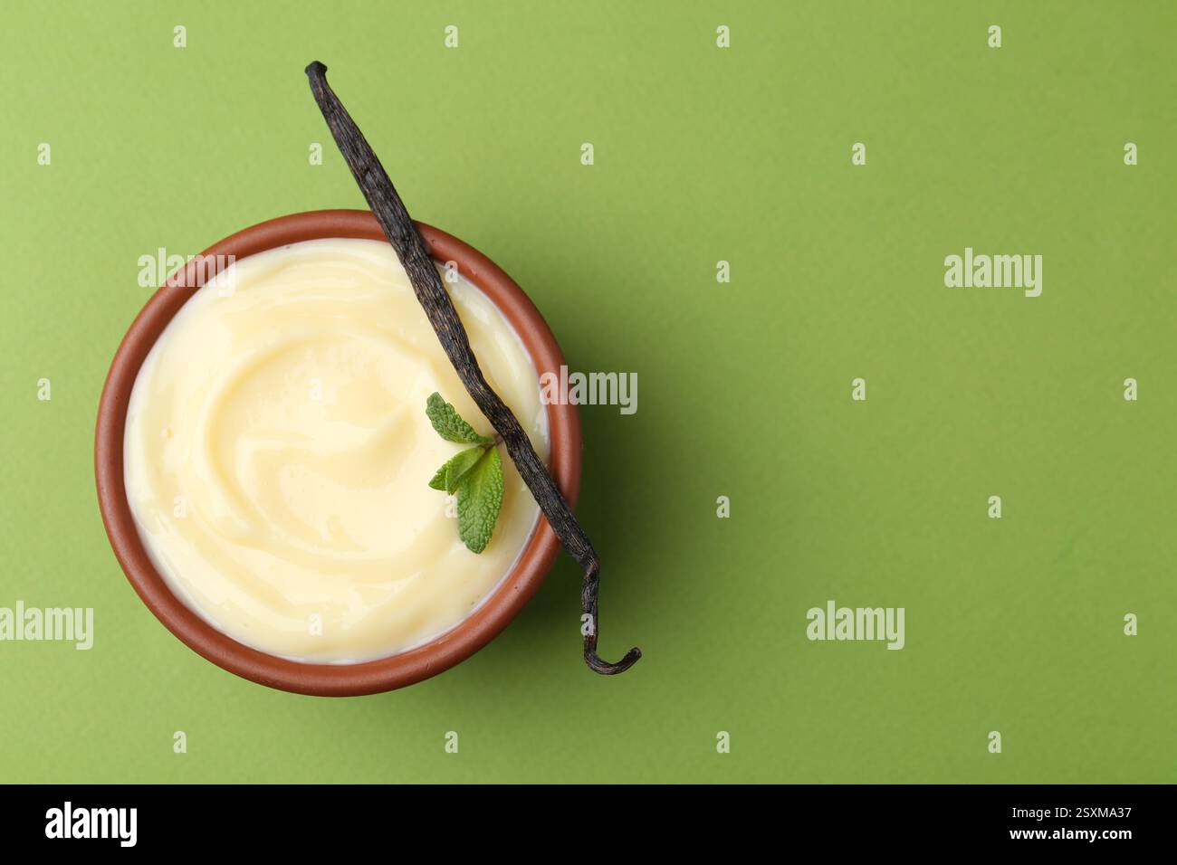 Tasty vanilla pudding, mint and pod on green background, top view ...