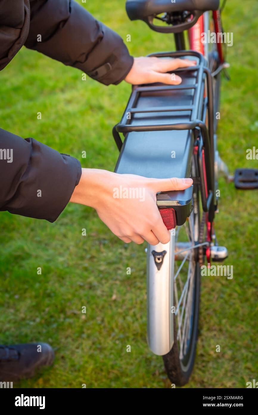 Hands installing and inserting battery on a frame on electric bike ...