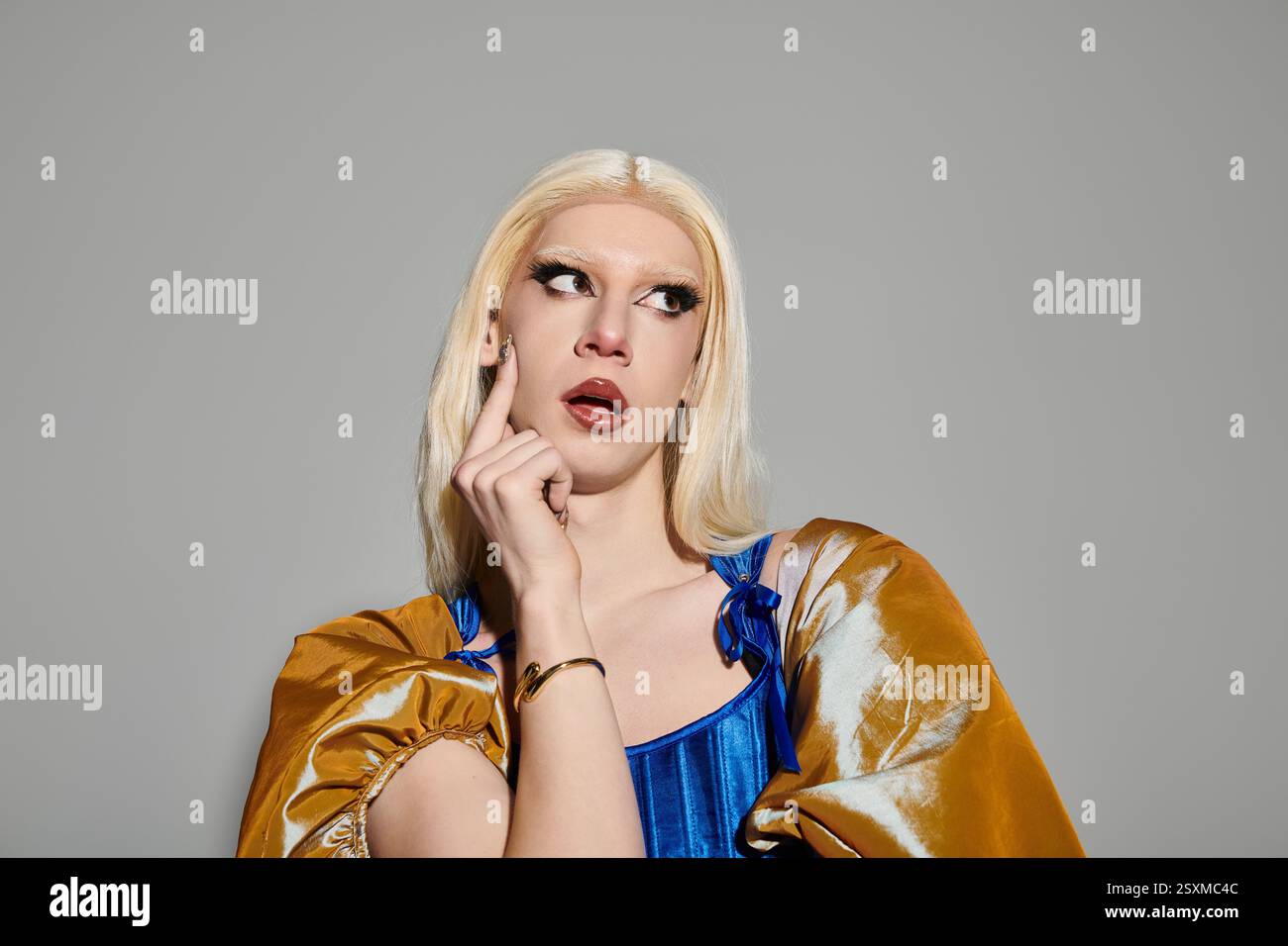 A confident young drag queen poses stylishly in a chic outfit and bold ...