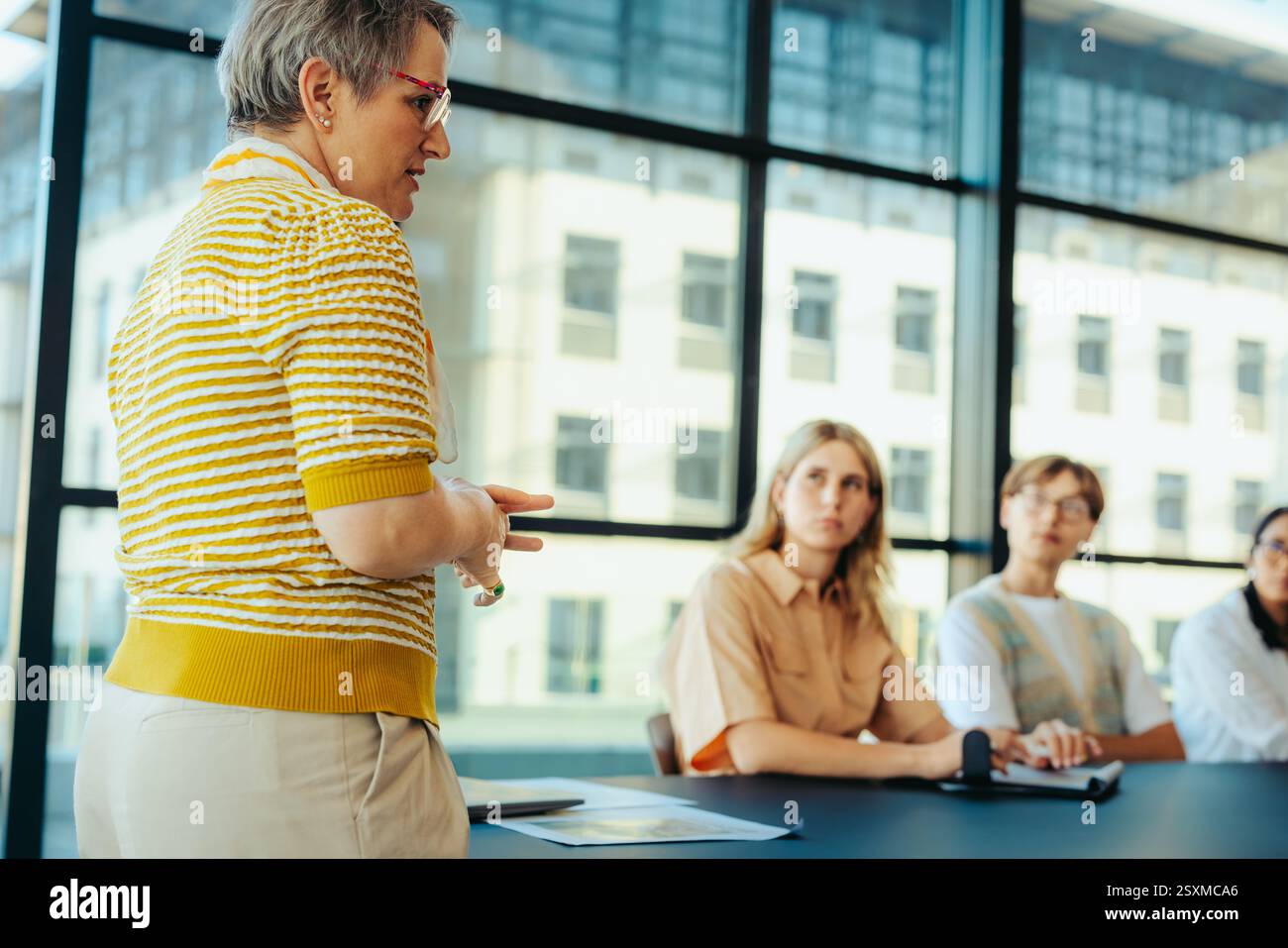 A teacher leads a small class of focused students in a modern setting ...