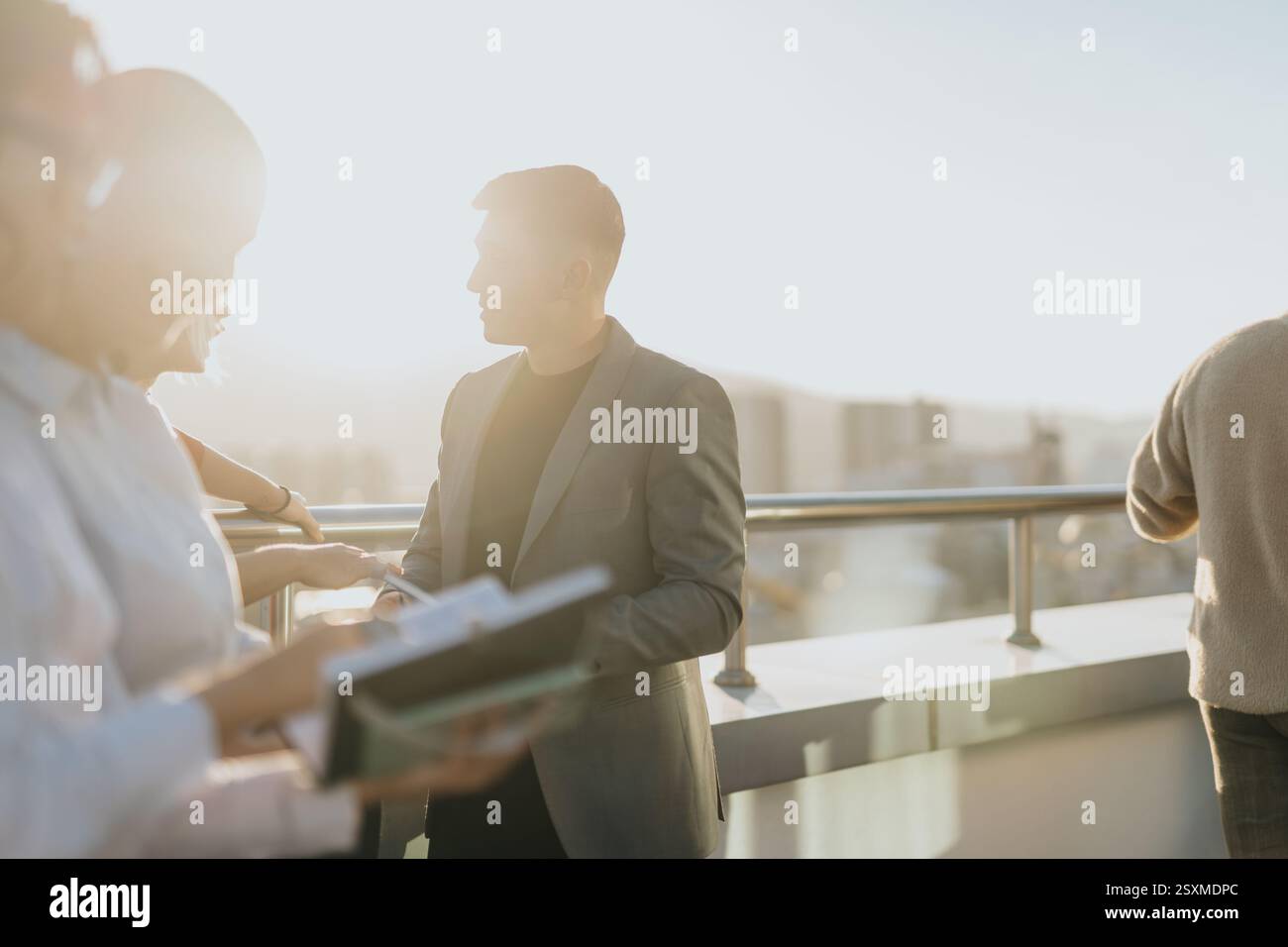 Group of business people standing on a high-rise balcony, discussing ...