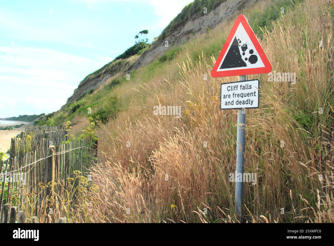 Unstable cliffs at Dunwich beach behind a cordon with warning sign ...