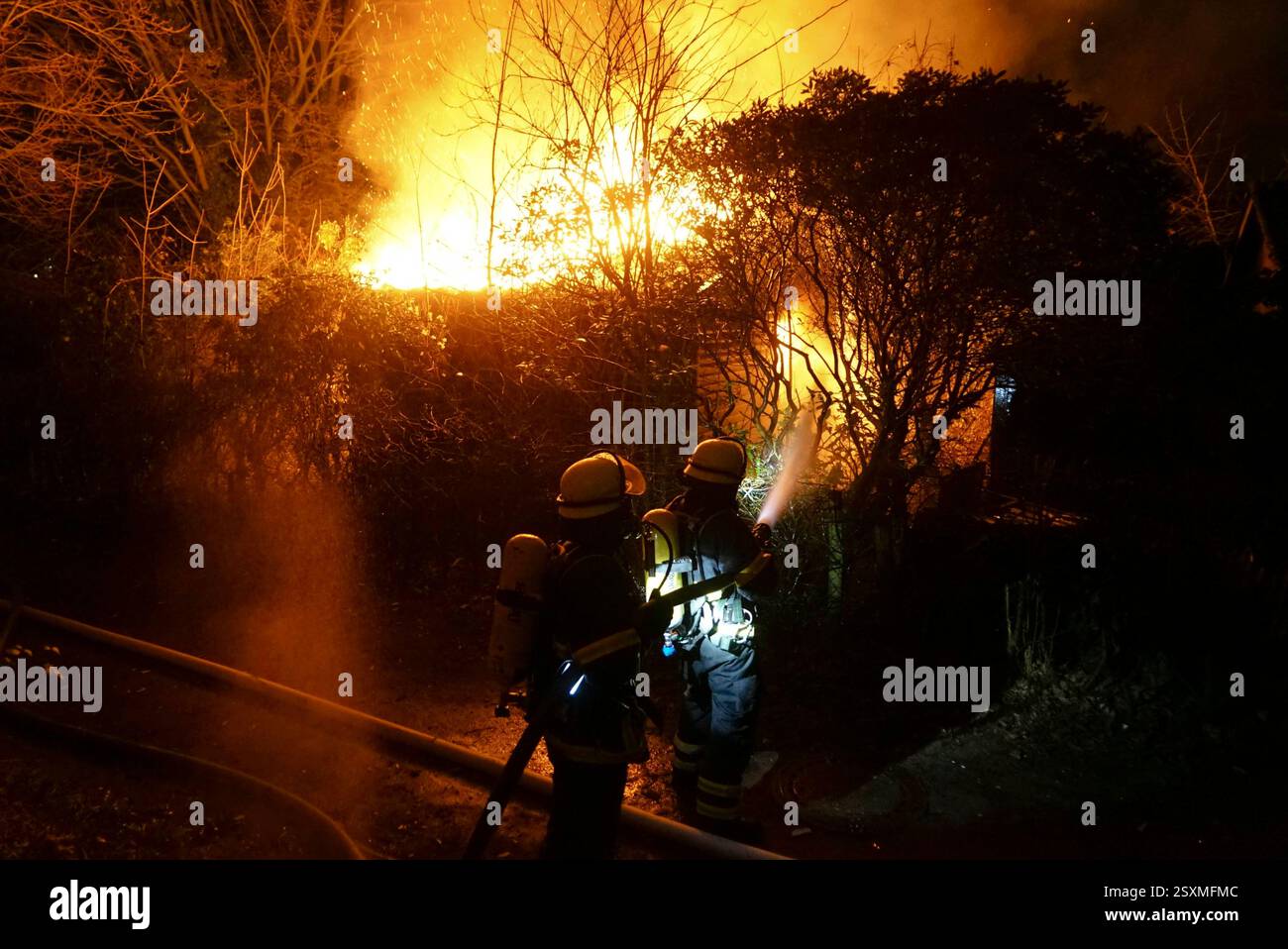 Feuwehrleute im Einsatz beim Loeschen lockerner Flammen beim Vollbrand ...
