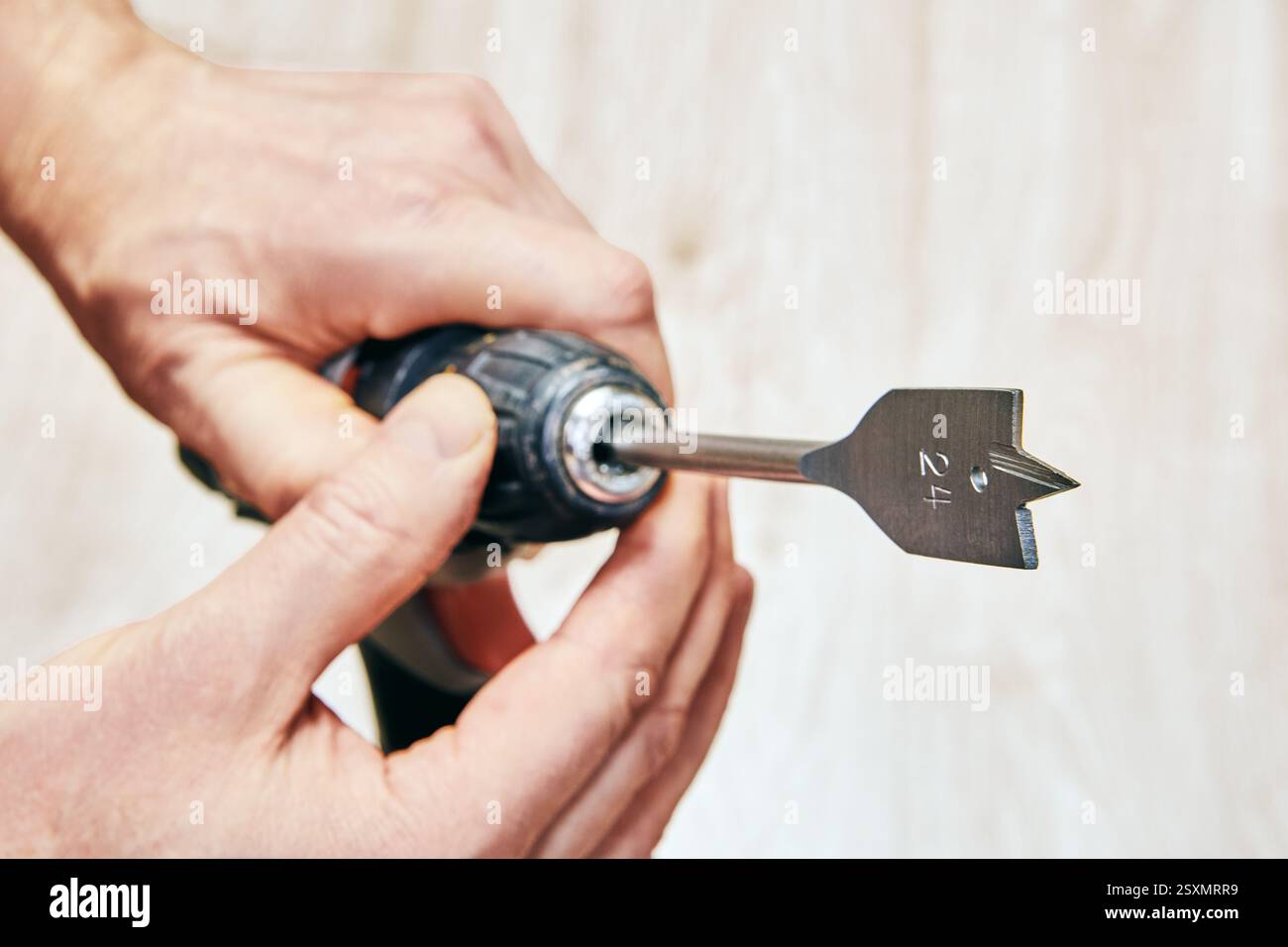 Drill chuck secures flat wood bit, while fingers adjust its position ...
