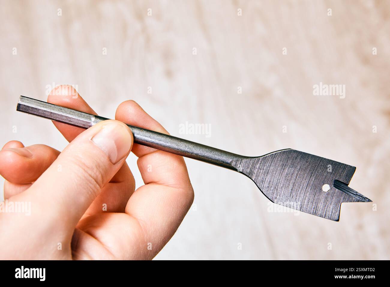 Wood drill bit, gripped by hand, reveals sharpened cutting edges at its ...