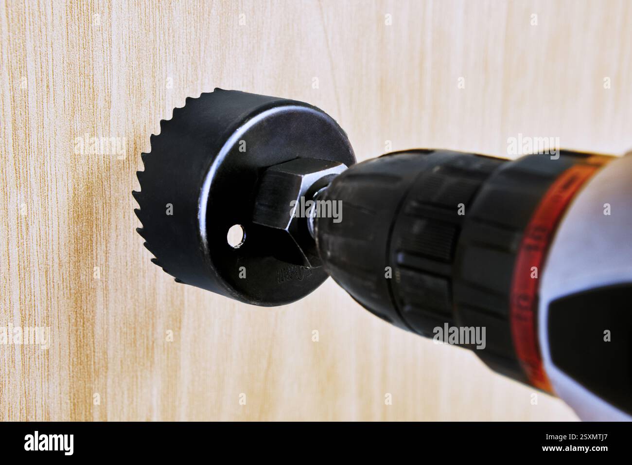 Power drill with sharp hole saw is prepared for creating door lock ...