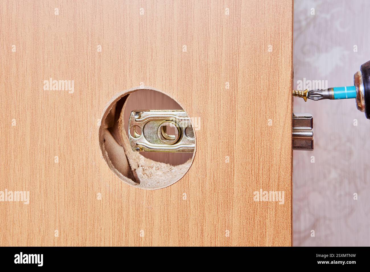 Door latch installation presents power drill driving screw into metal ...