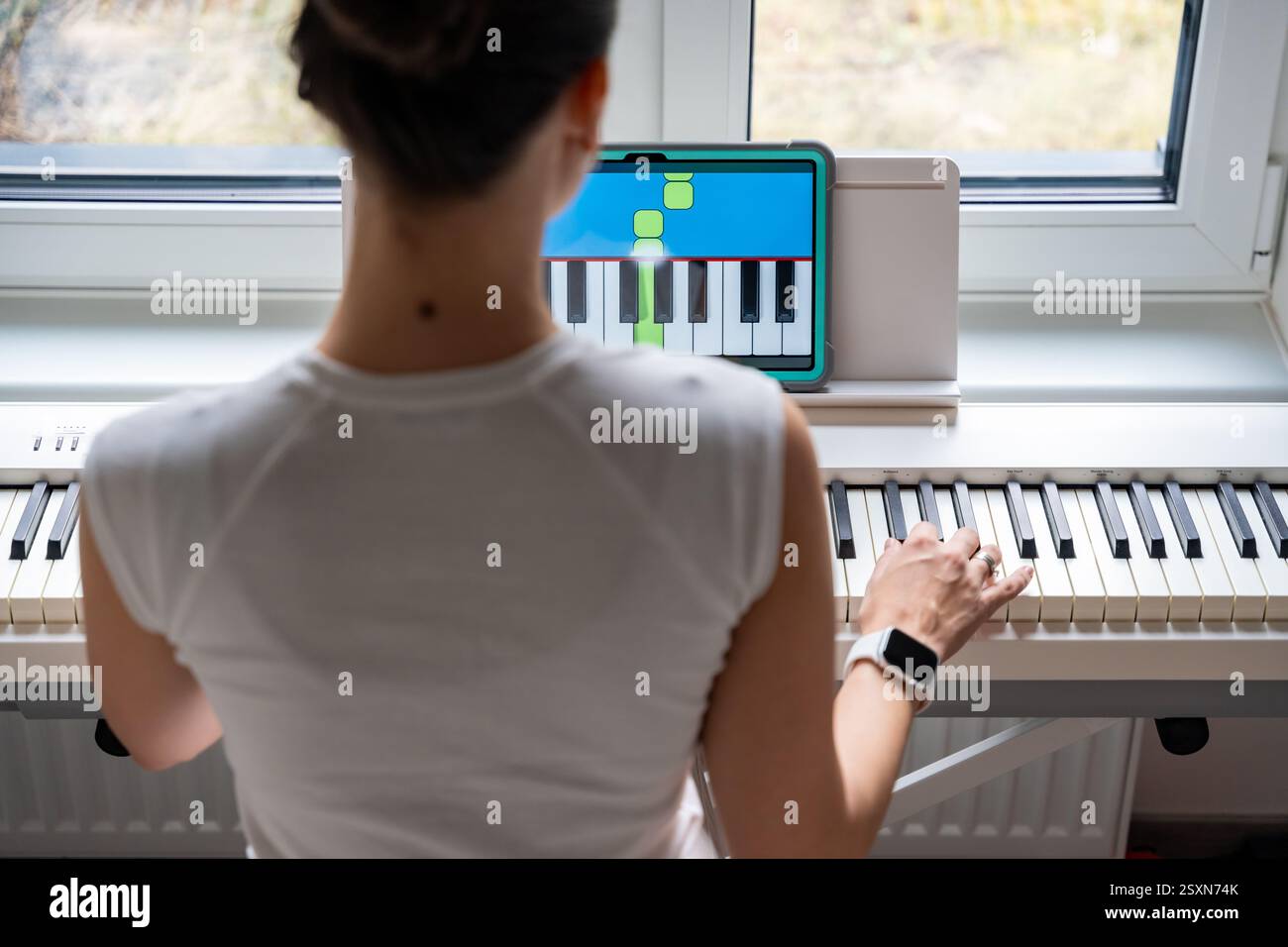 Young woman learning to play the keyboard at home using an interactive ...