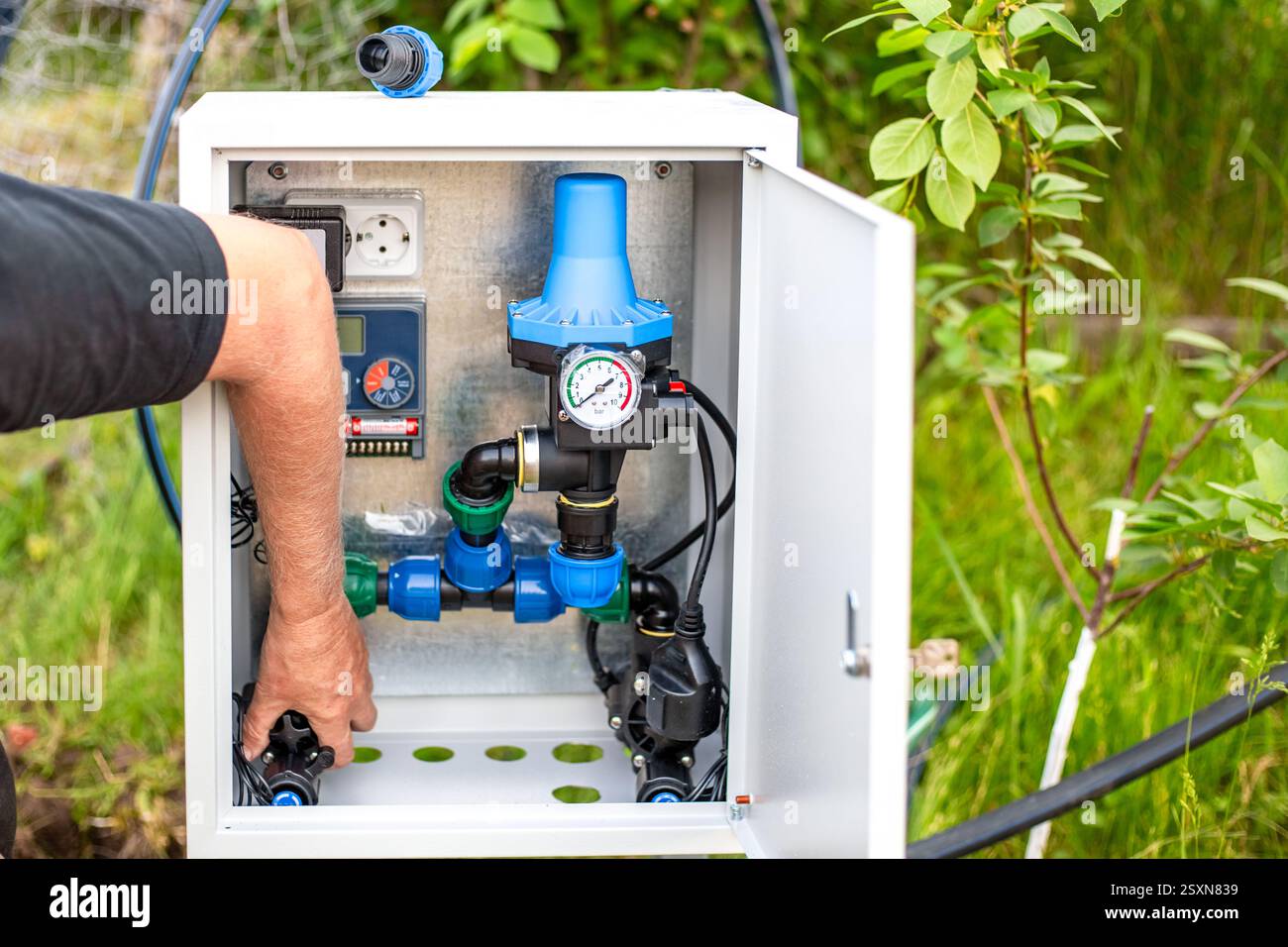 Installation of a drip irrigation system. A man installs an Automatic ...