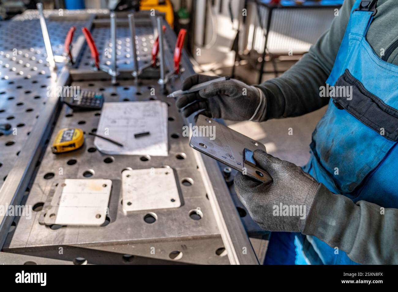 Metalworker marking measurements on metal plate in workshop Stock Photo ...