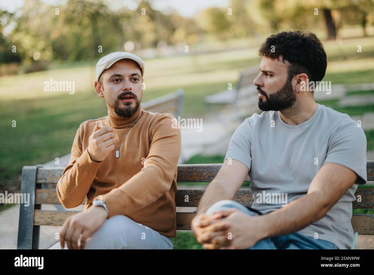 Two men having a thoughtful conversation on a park bench outdoors Stock ...