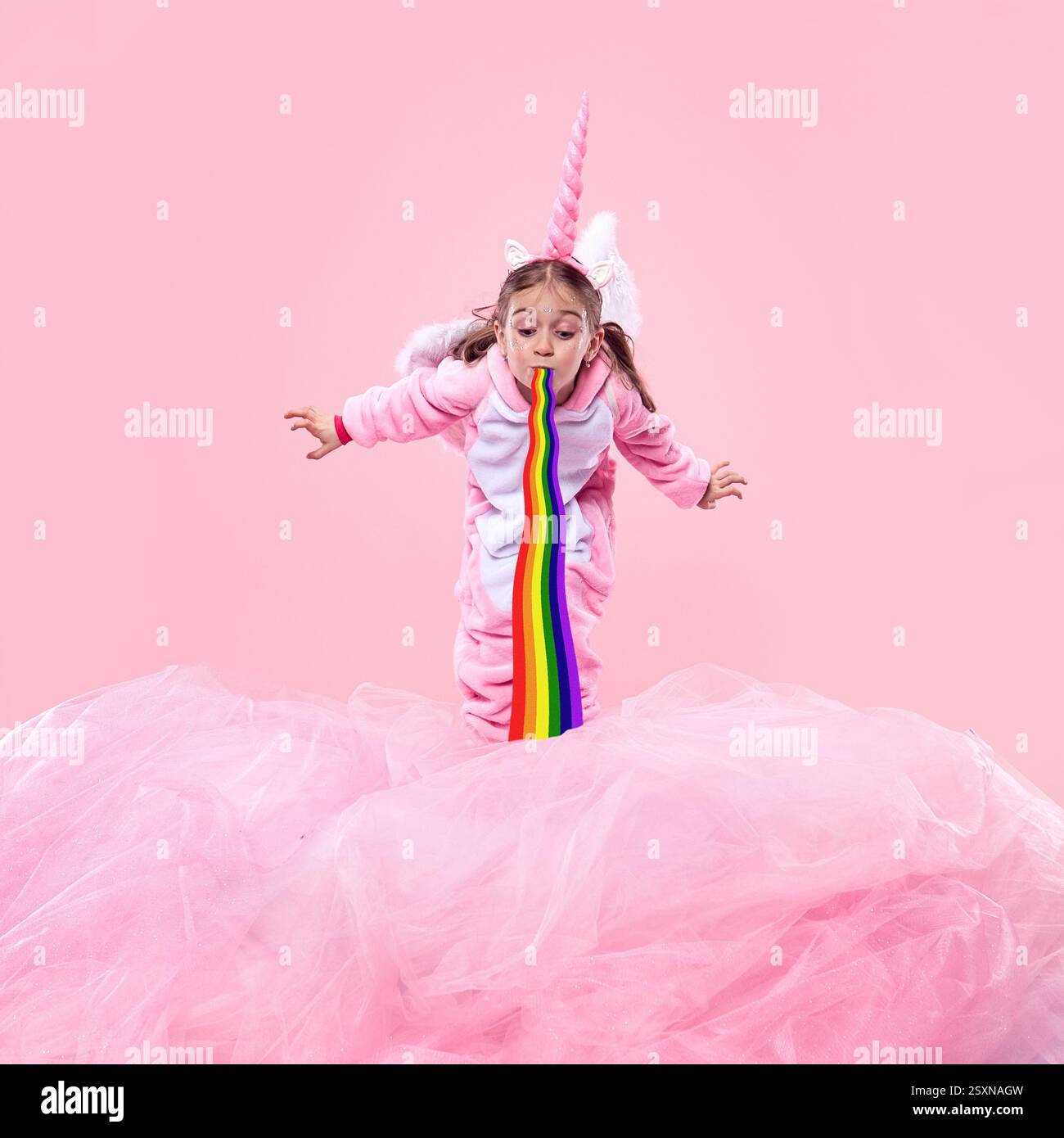 Child in unicorn costume leans forward, rainbow stream pouring from ...