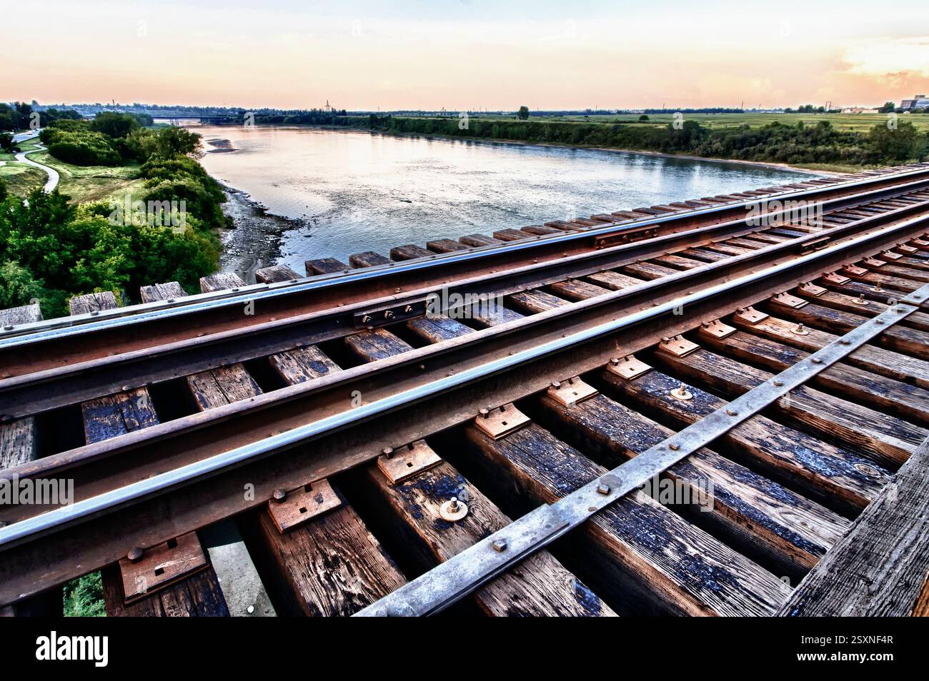 The train tracks are old and rusty, and the water below is calm. The ...