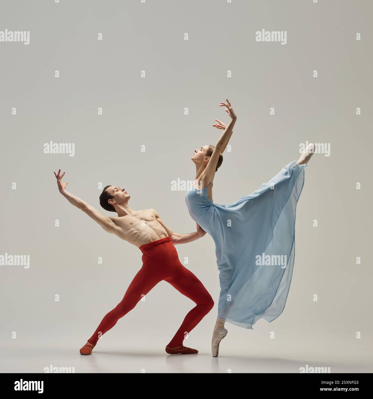 Ballerina lifting leg high in dramatic extension while partner holds ...