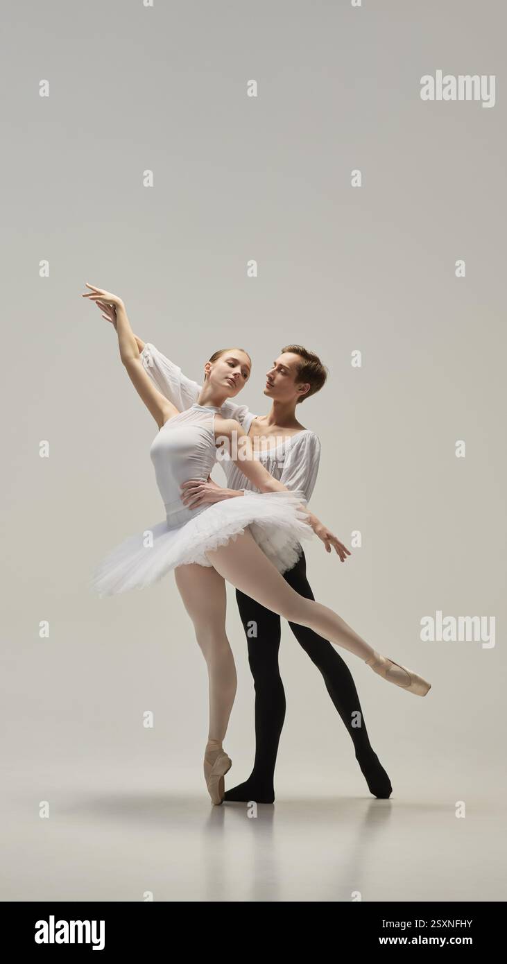 Ballerina extending arm in classical pose, partner standing behind in ...