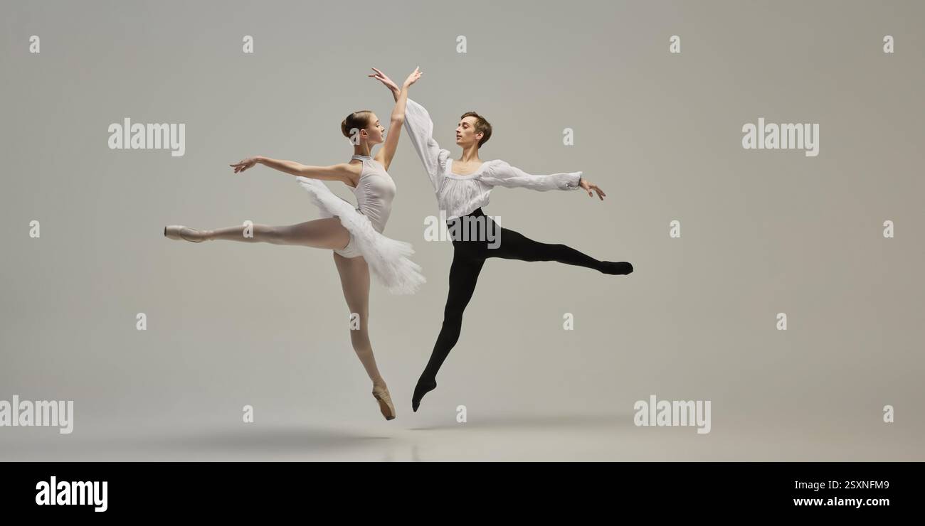 Two ballet dancers leaping in perfect synchronization, arms reaching ...