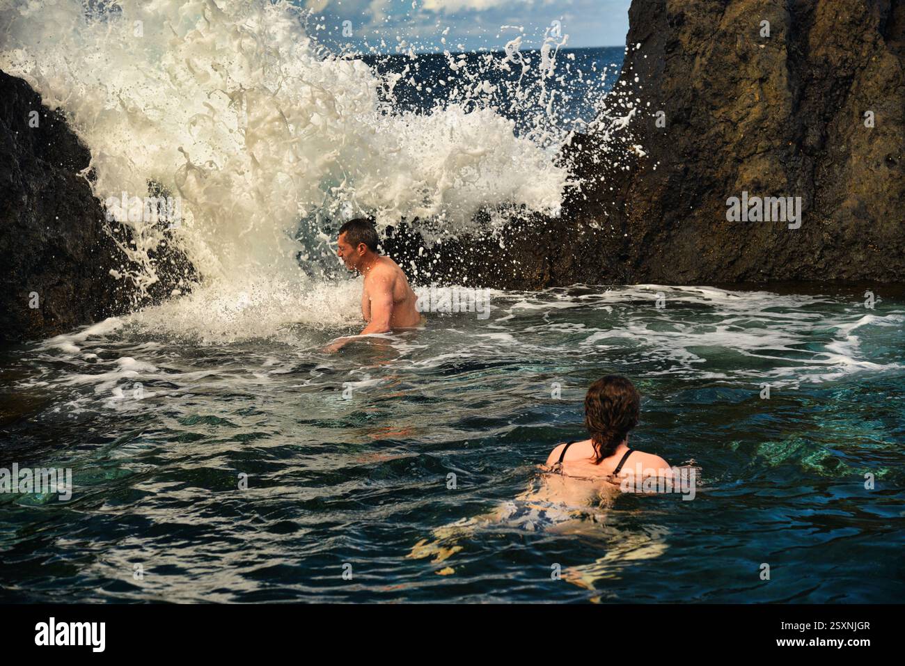 Father and daugher swimming in coastal swimming pools, El Caleton, within lava rock outcroppings ...