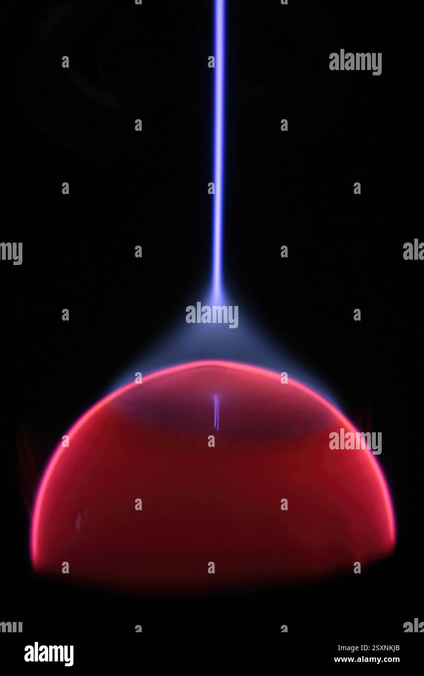Purple beam of plasma hitting a red hemisphere in a dark room, creating ...