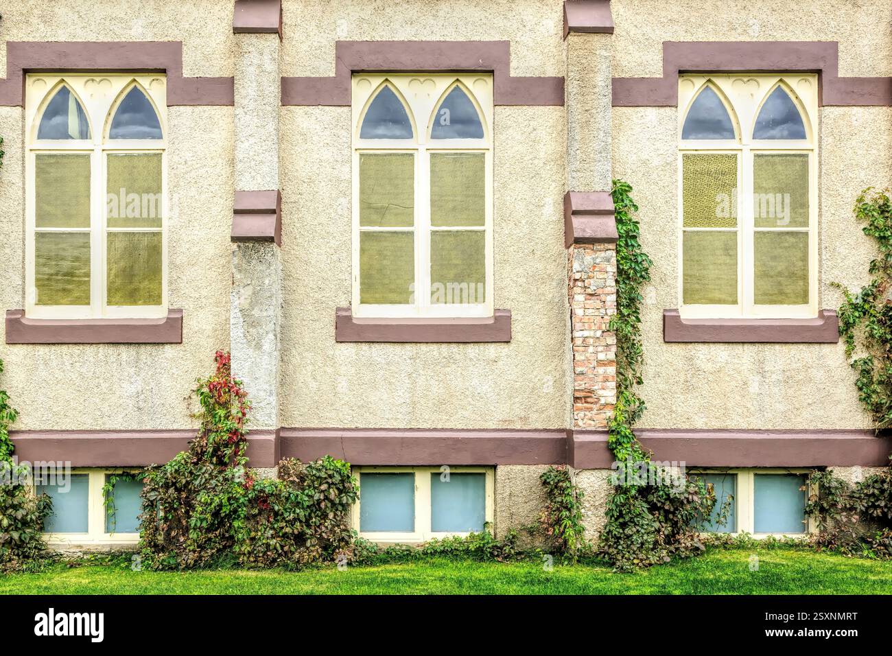 Building with three windows and a brick wall. The windows are covered ...