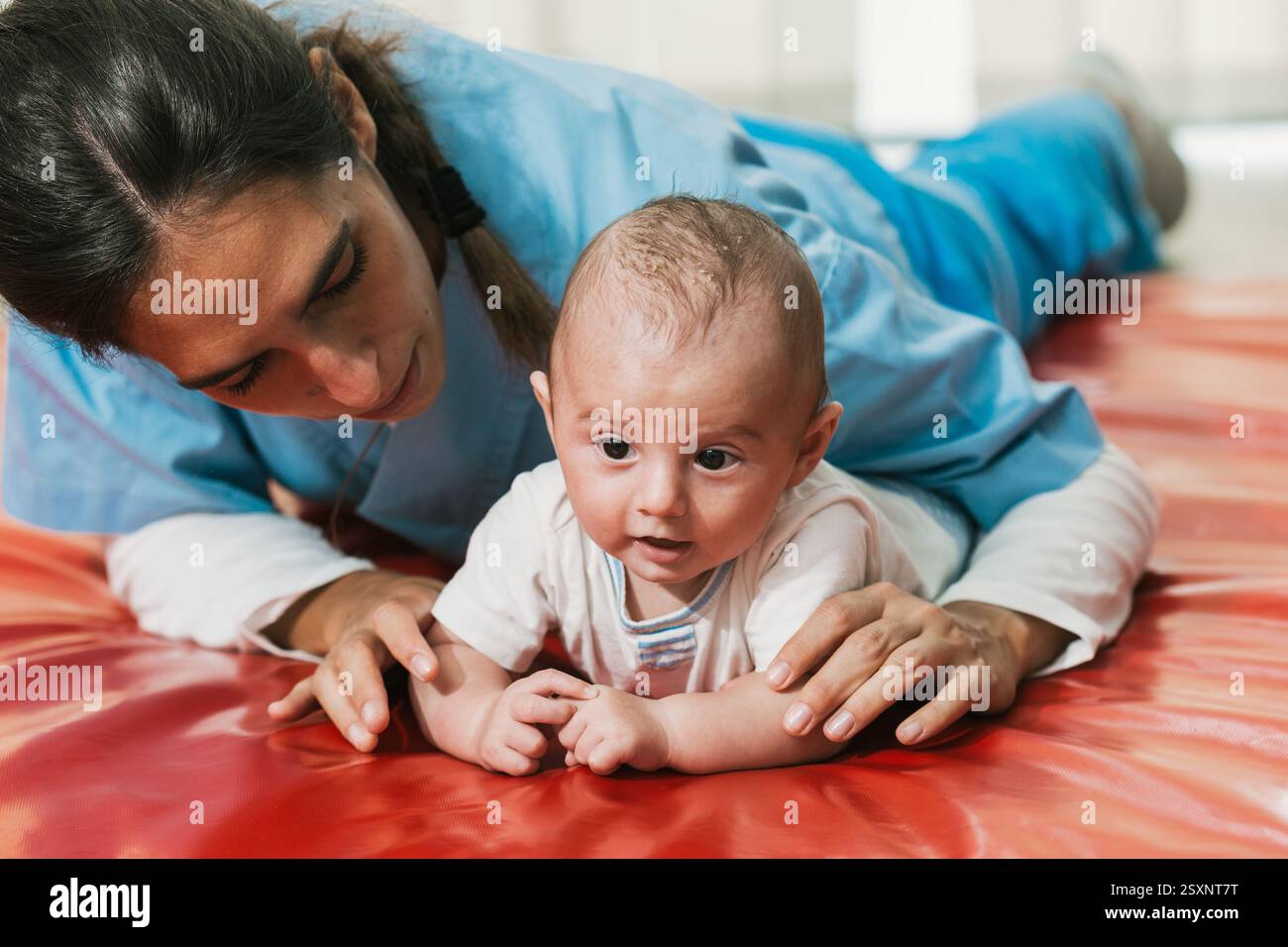 Physiotherapist assisting baby with prone position and head control ...