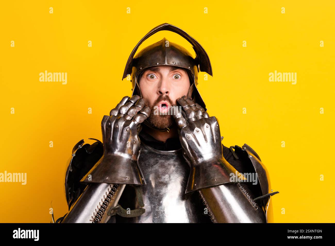 Surprised knight in medieval armor posing on vibrant yellow background ...