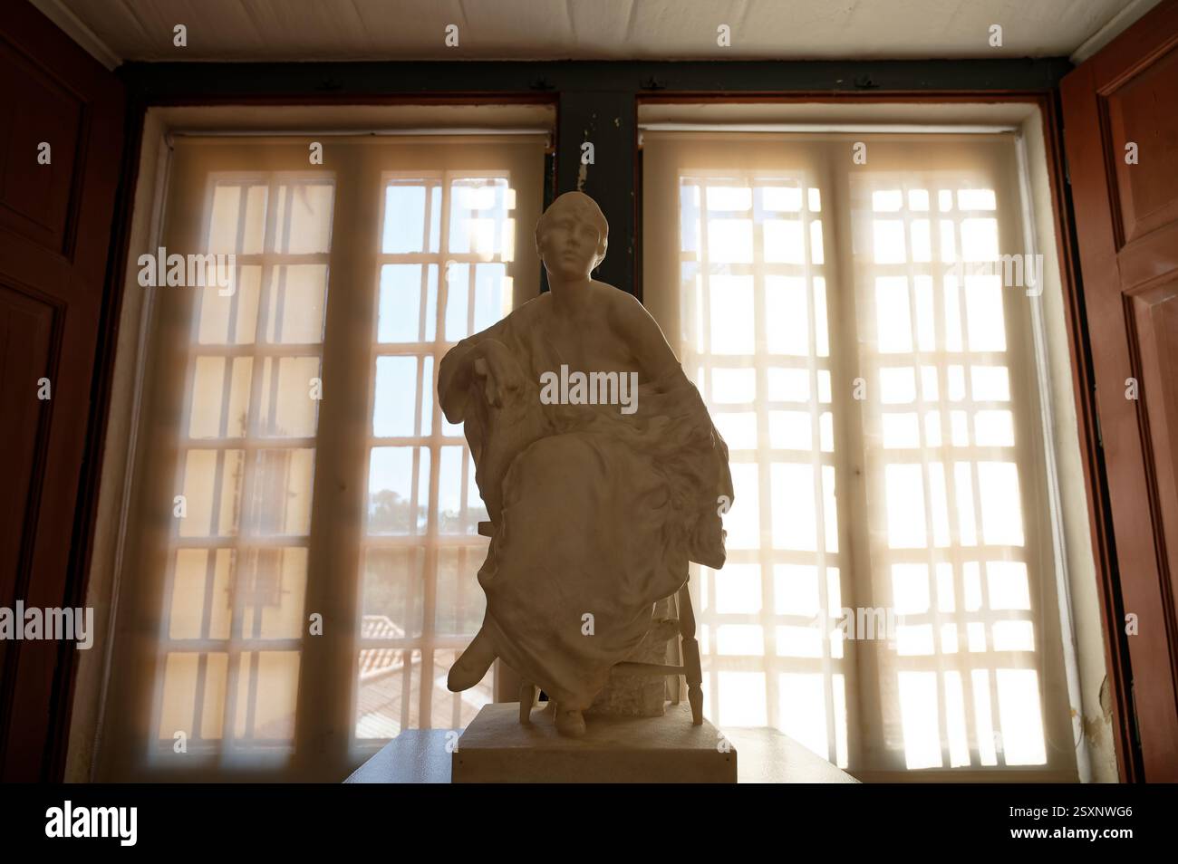 Marble statue of a seated woman draped in flowing robes, illuminated by ...