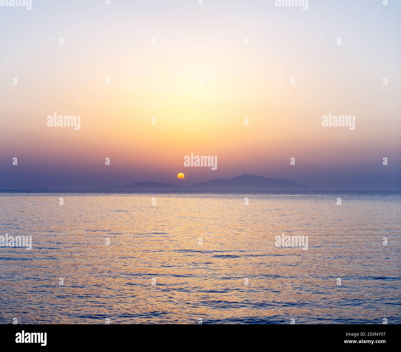 Stunning sunrise over calm sea waters with distant islands in the ...