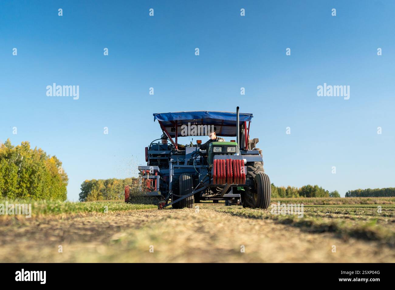 A Farm Tractor is Actively Working in the Open Field Beneath a Clear ...