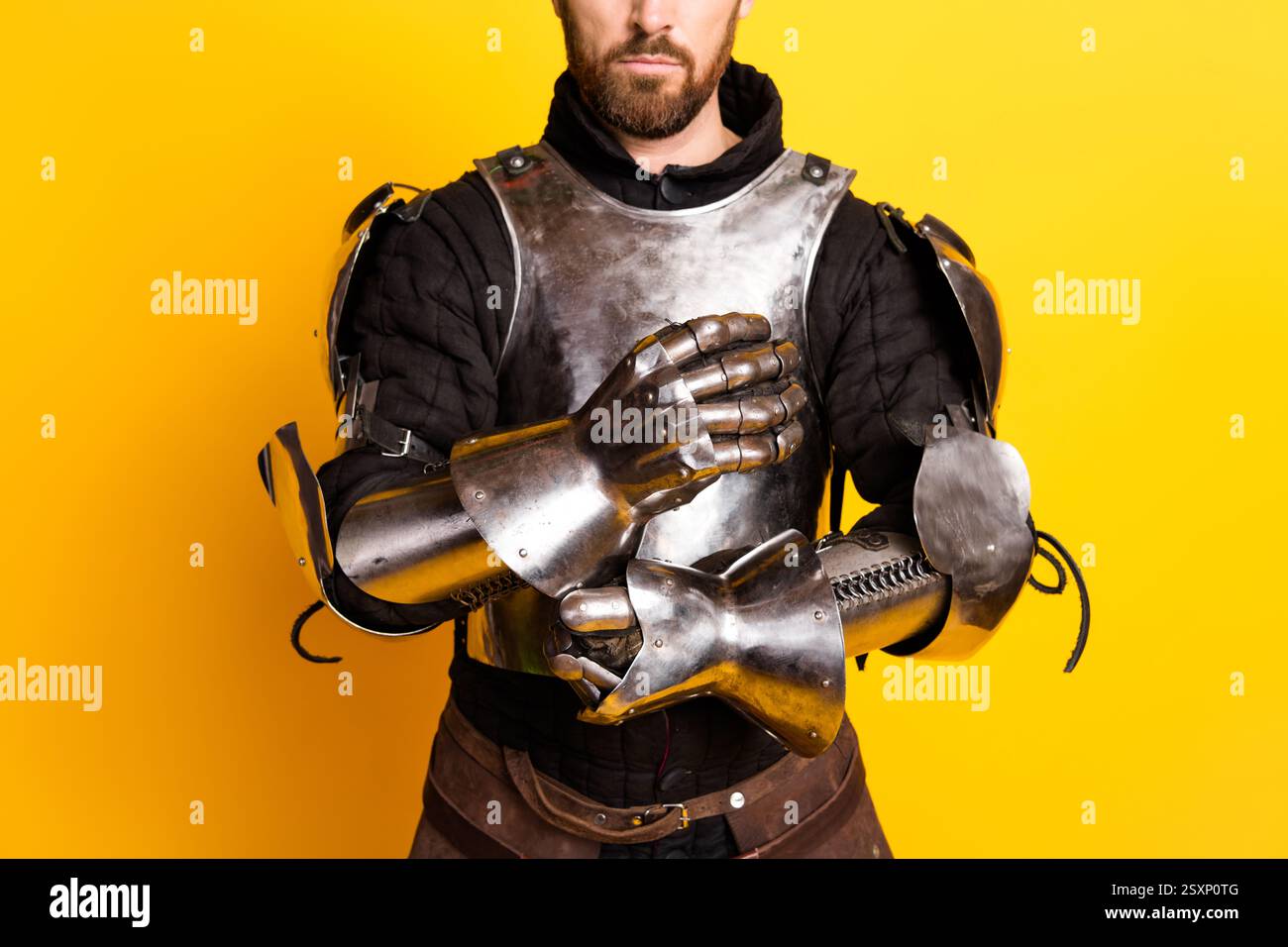 Medieval knight in shining armor posing against bright yellow ...