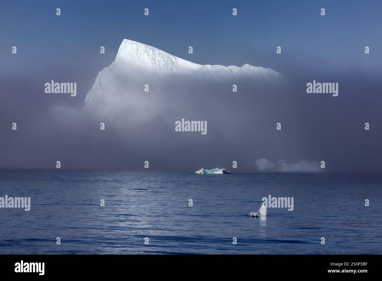 Giant iceberg with the tip picked out in sunlight and much of the base ...