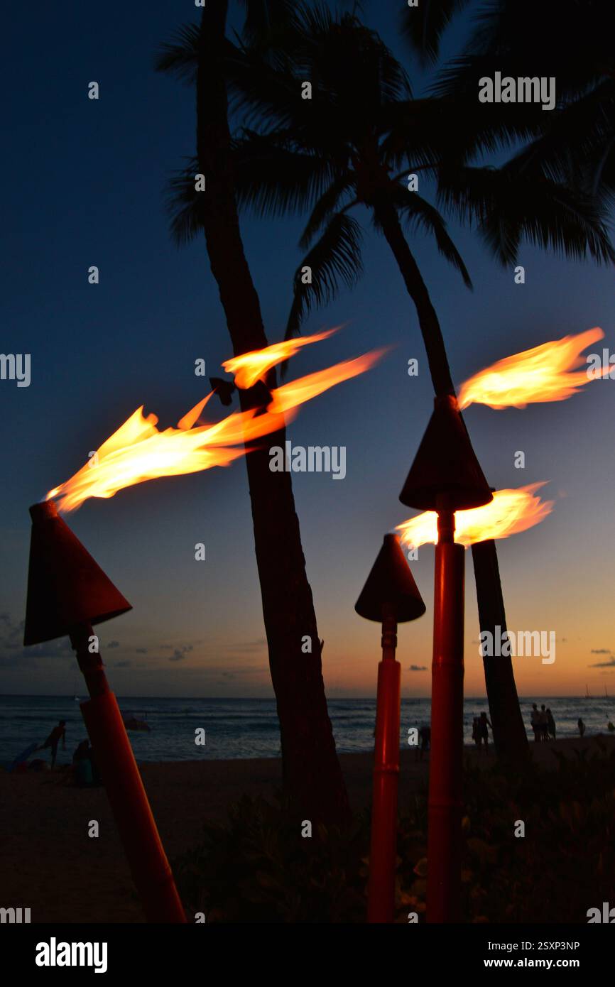 Traditional and cultural torches burn at dusk on Waikiki Beach in ...