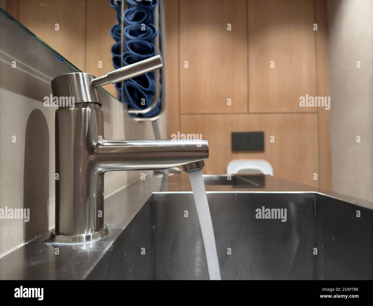 Modern aluminum sink with open tap and warm water flowing into the sink ...