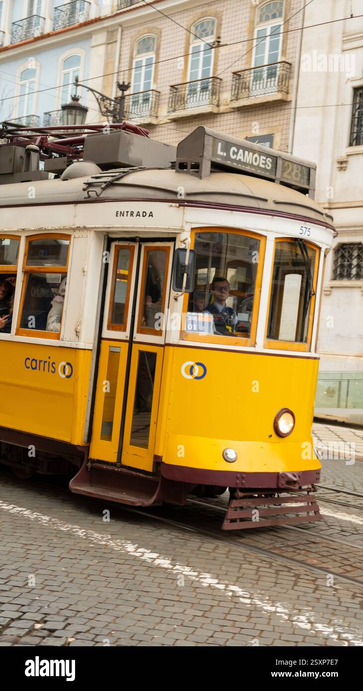 A traditonal old style tram heading down a hill in the Alfama old town ...